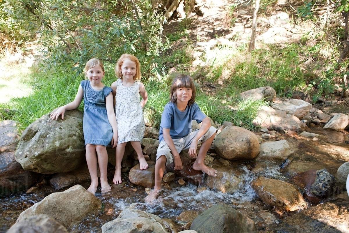 Child on rocks by river - Stock Photo - Dissolve