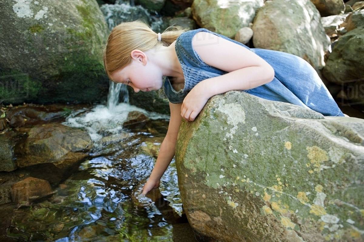 Girl on rock by river - Stock Photo - Dissolve