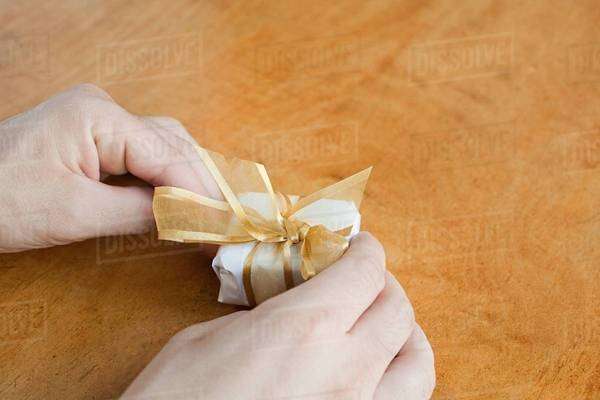 Person wrapping small gift - Stock Photo - Dissolve