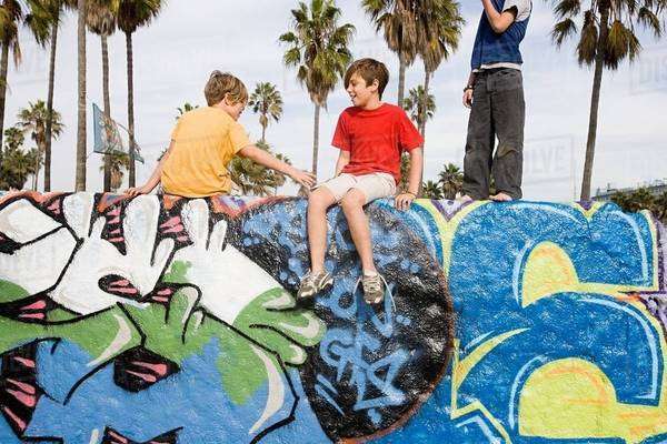 Three boys sitting on wall with graffiti - Royalty-free Stock Photo ...