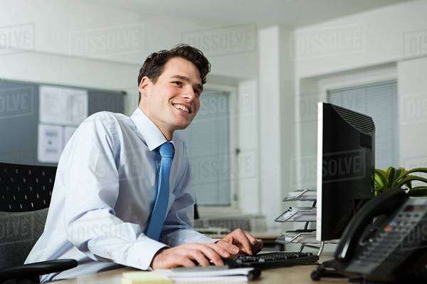 Office worker sitting at desk, smiling - Royalty-free Stock Photo ...