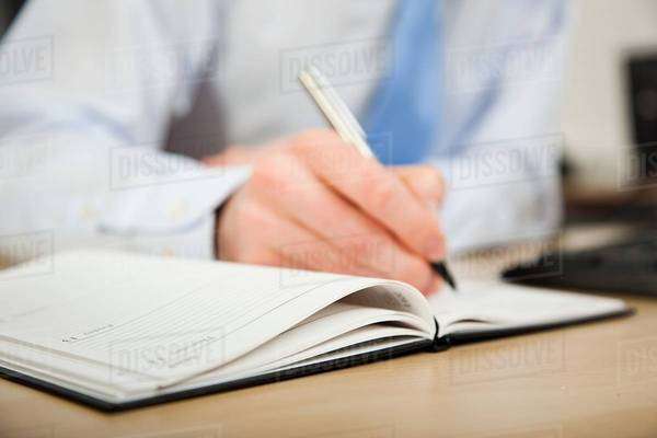 Office worker writing in diary - Royalty-free Stock Photo | Dissolve