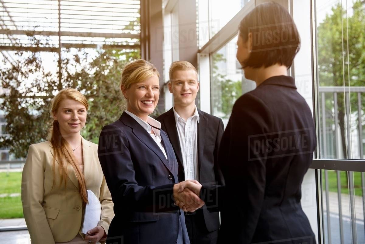Business team greeting young female colleague - Stock Photo - Dissolve