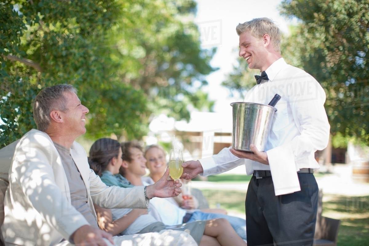 Waiter serving customers in garden - Royalty-free Stock Photo | Dissolve