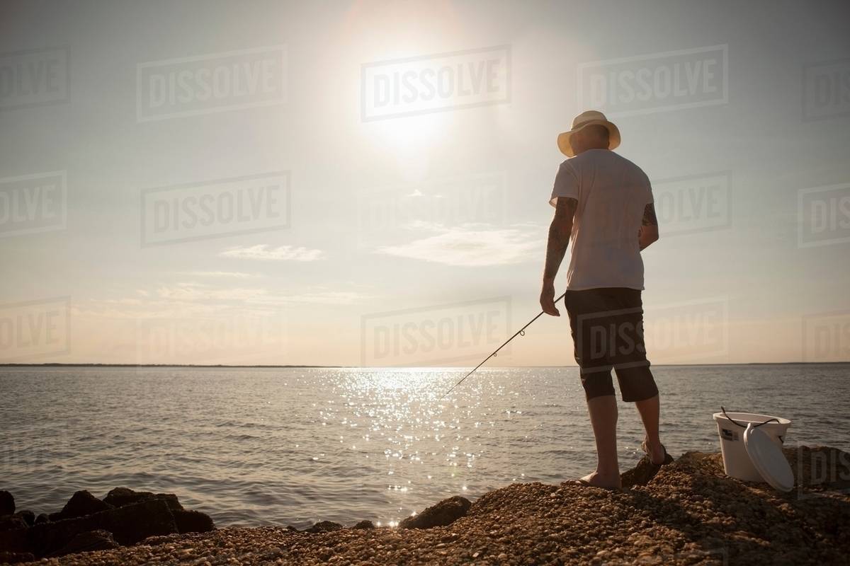 Man fishing in still ocean - Royalty-free Stock Photo | Dissolve
