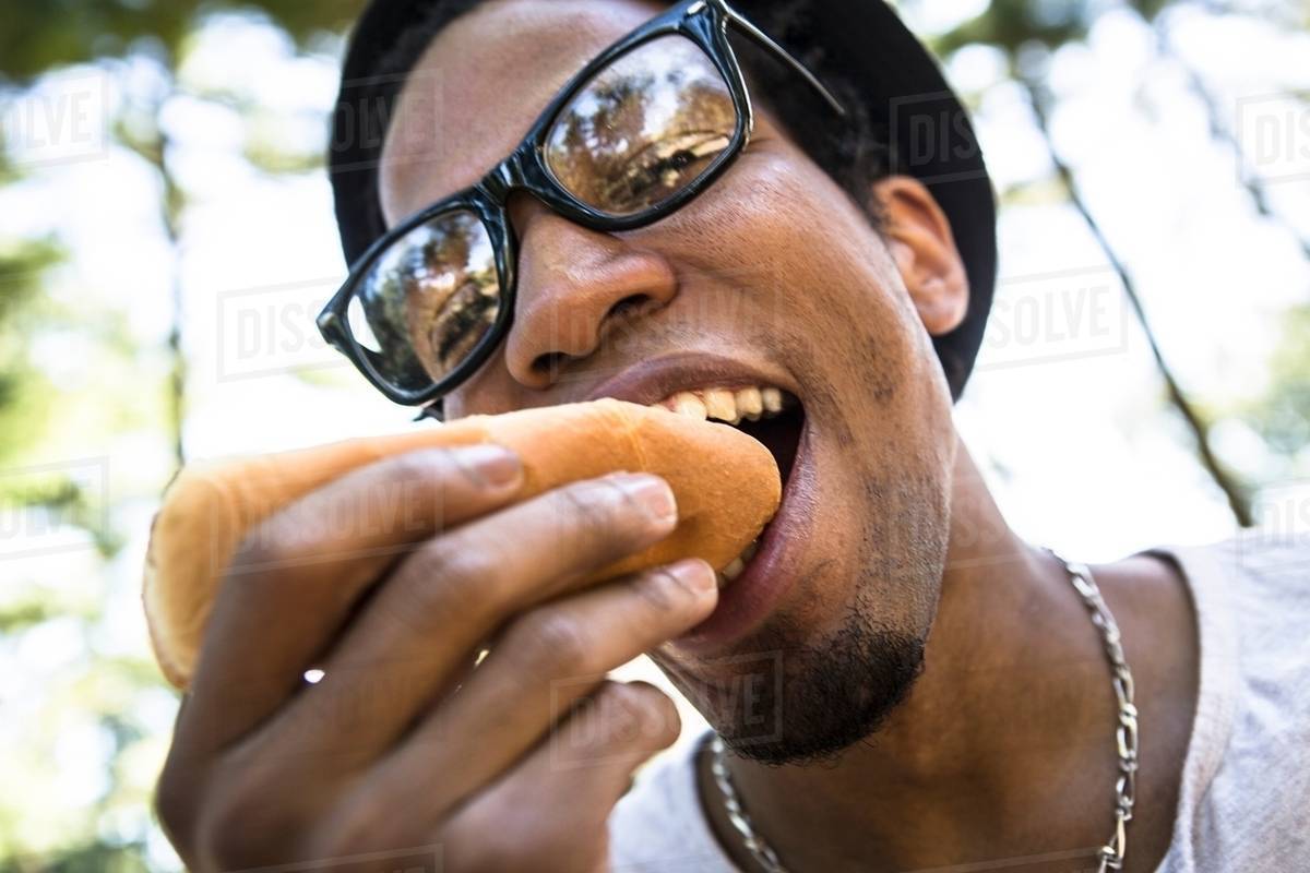 Young man eating bread roll - Royalty-free Stock Photo | Dissolve