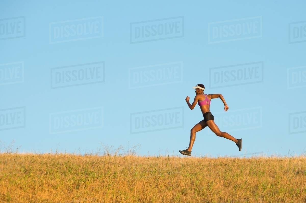 Young woman running across field - Royalty-free Stock Photo | Dissolve