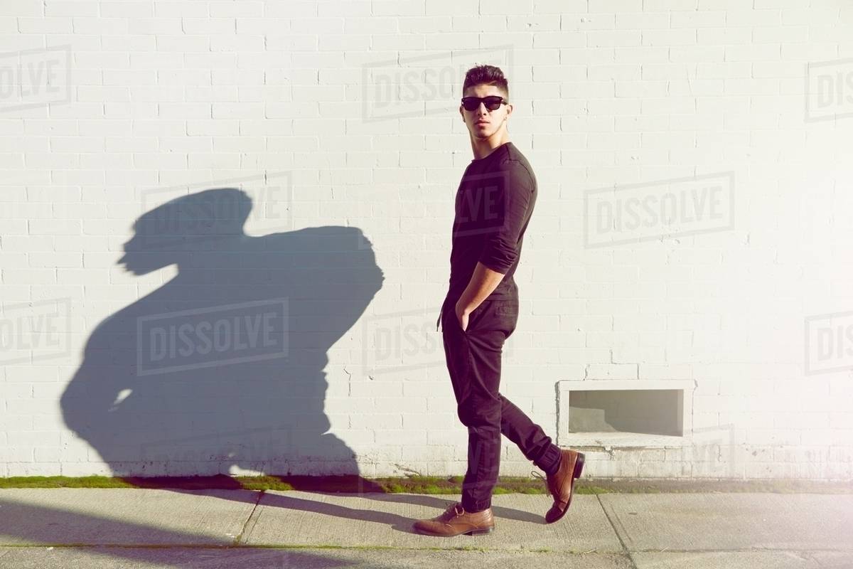Young man walking past white wall - Royalty-free Stock Photo | Dissolve