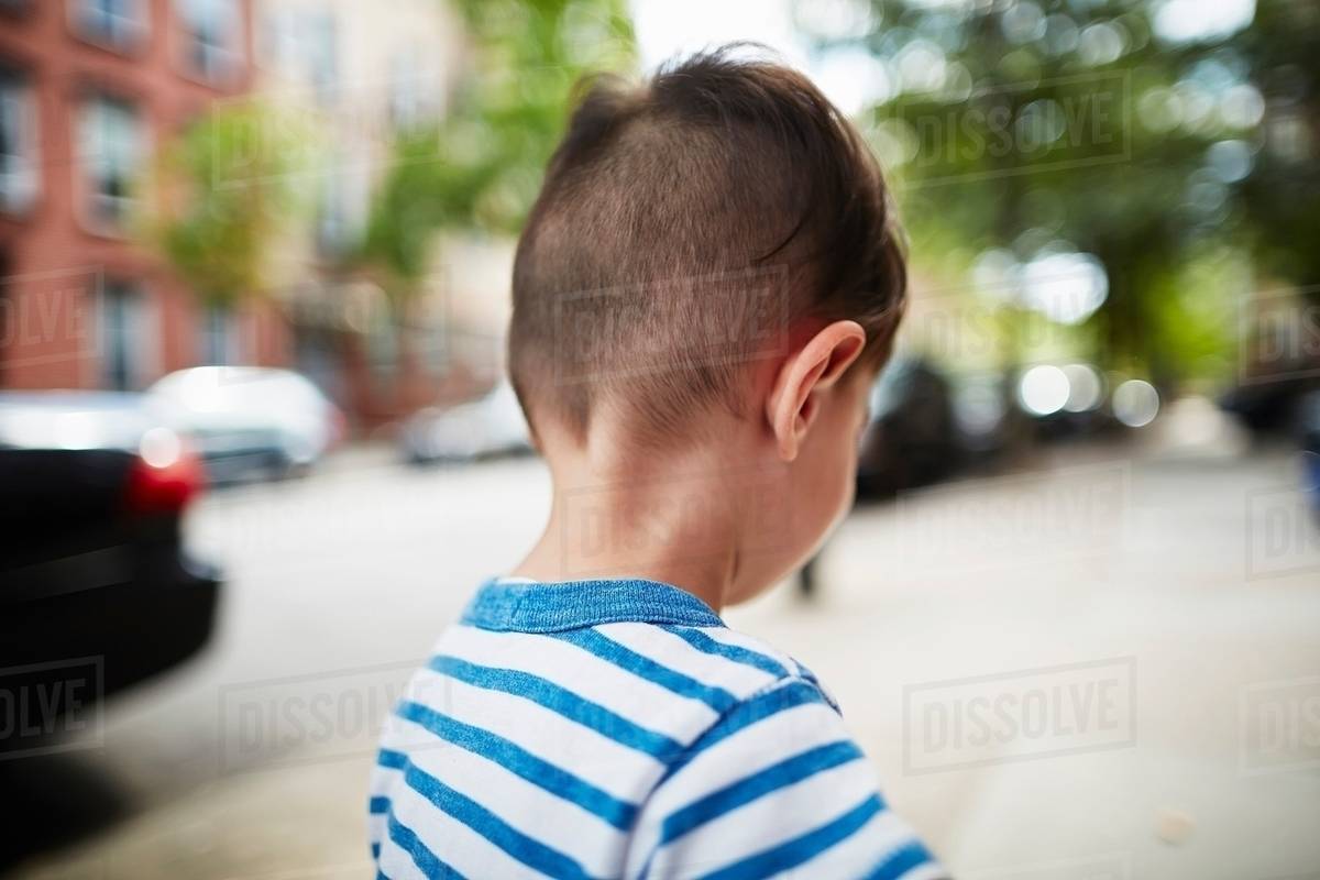 Back view of boy walking down street - Stock Photo - Dissolve