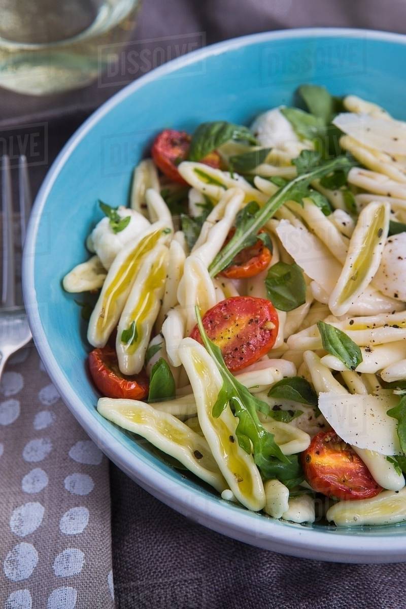 Close up of pasta salad with rocket and tomatoes - Stock Photo - Dissolve