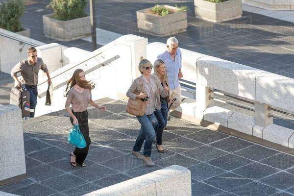 Five adults walking across elevated walkway - Stock Photo - Dissolve