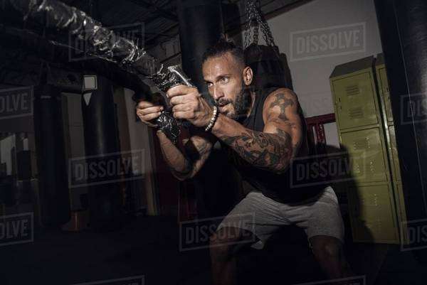 Male boxer pulling battle rope in gym - Stock Photo - Dissolve