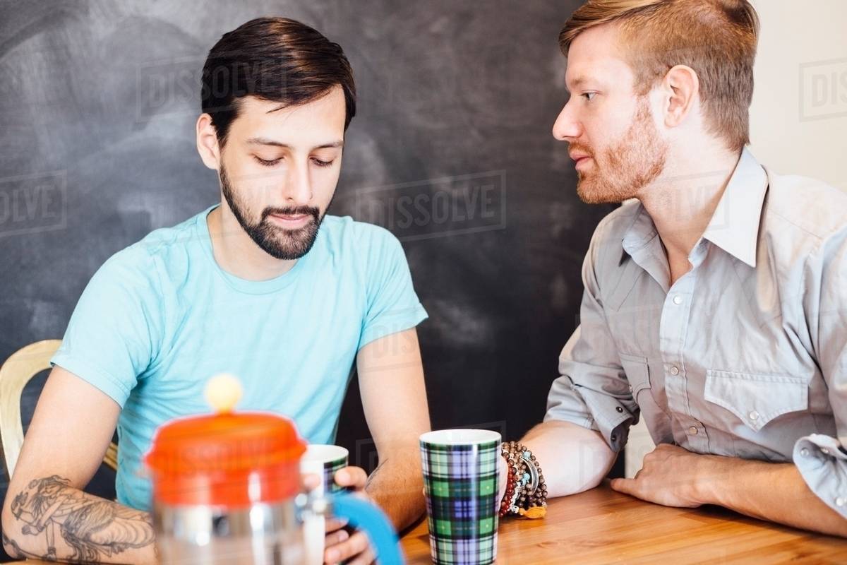 Male couple sitting at table, drinking coffee - Royalty-free Stock ...