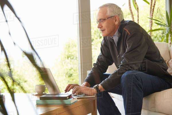 Senior man at home, using laptop - Stock Photo - Dissolve