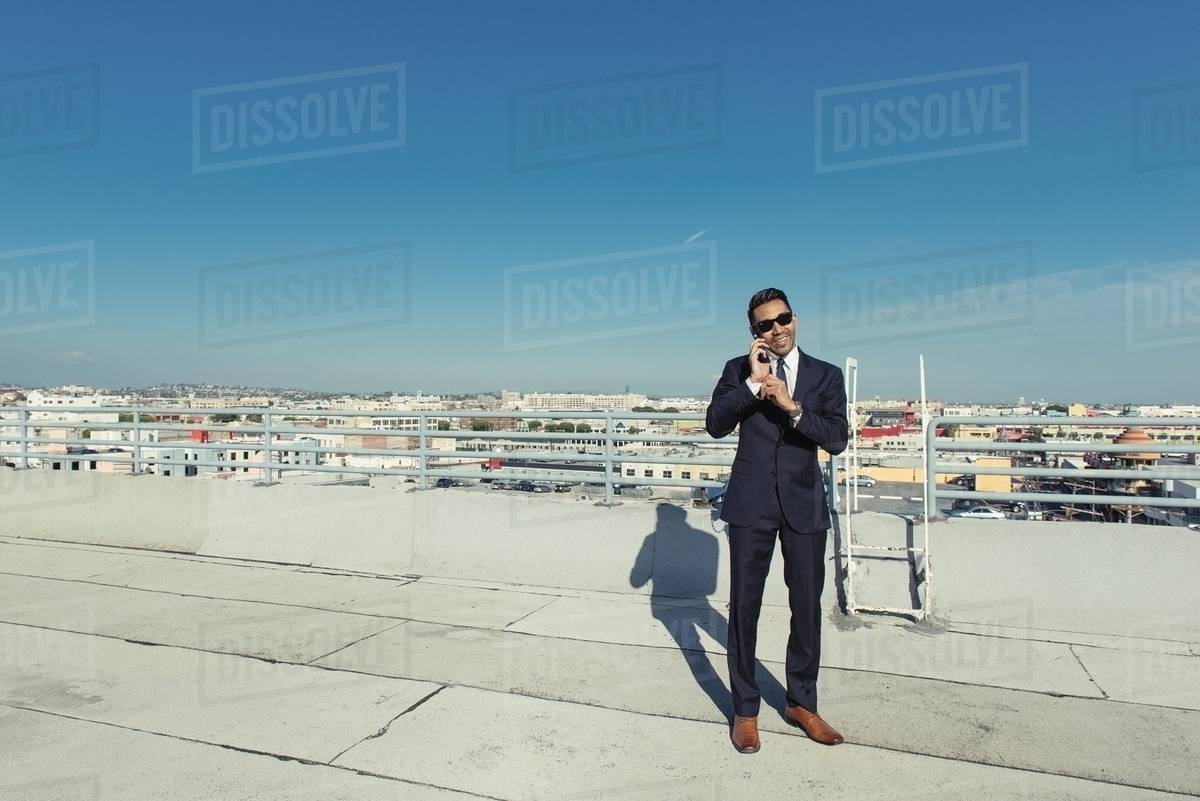 Businessman speaking on smartphone on roof terrace, Los Angeles ...