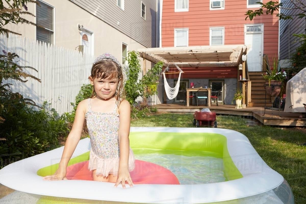 Girl sitting on inflatable floating in pool - Stock Photo - Dissolve