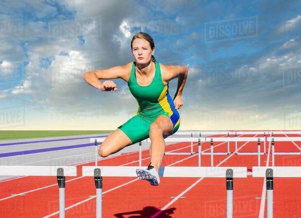 Runner jumping over hurdle on track - Royalty-free Stock Photo | Dissolve