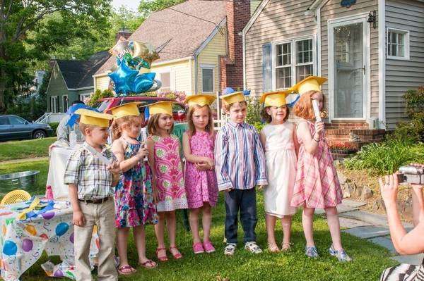 Group of children at kindergarten graduation, wearing paper mortar ...