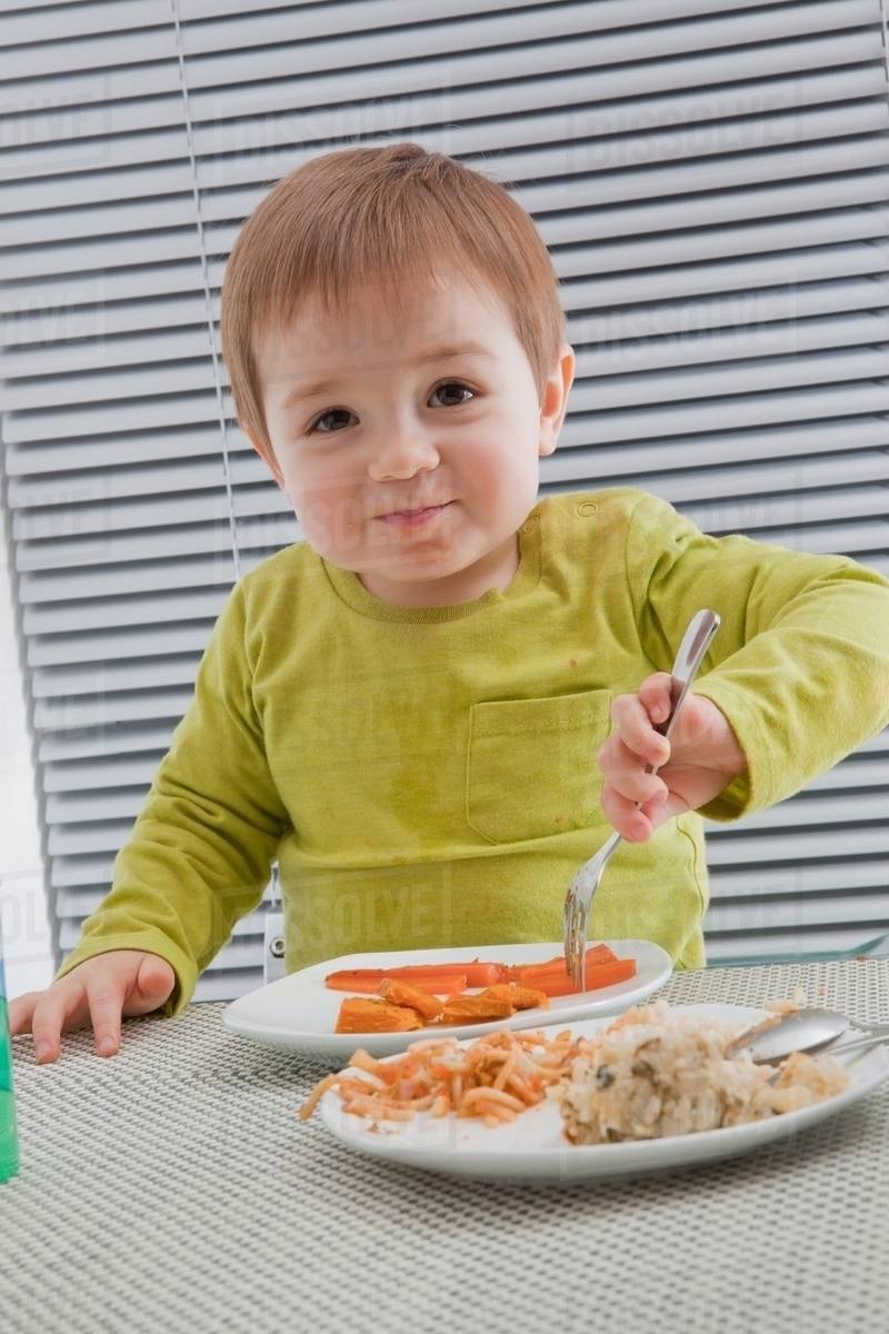 Baby boy feeding himself at dining table - Royalty-free Stock Photo ...