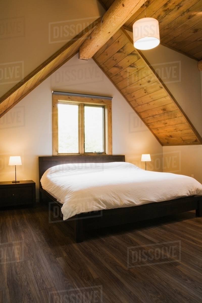 Vaulted ceiling and double bed below window in modern bedroom - Stock ...