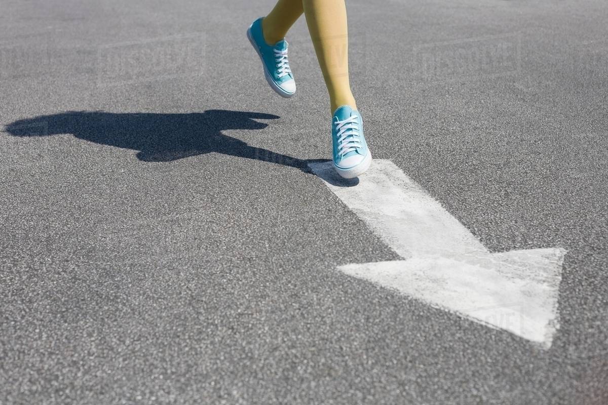 Woman running on a direction arrow - Royalty-free Stock Photo | Dissolve