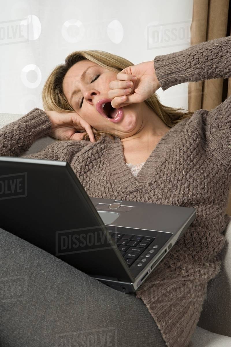 Yawning woman with laptop - Royalty-free Stock Photo | Dissolve