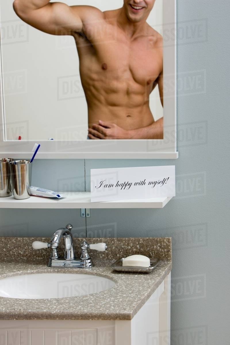 A happy young man looking in a mirror - Royalty-free Stock Photo | Dissolve