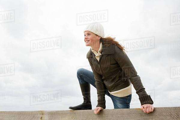 Woman climbing over wall - Stock Photo - Dissolve