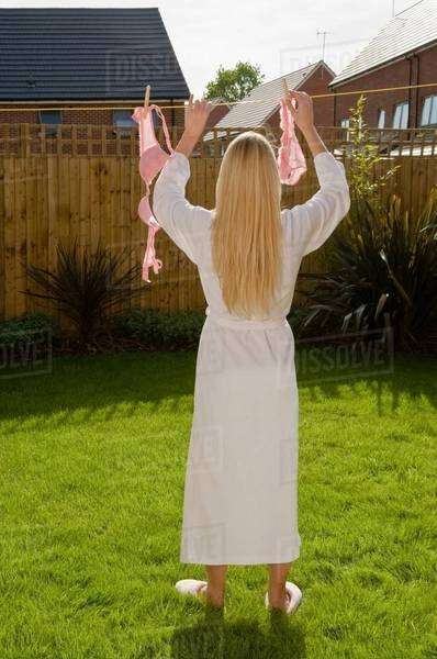 Woman putting lingerie in washing line - Stock Photo - Dissolve