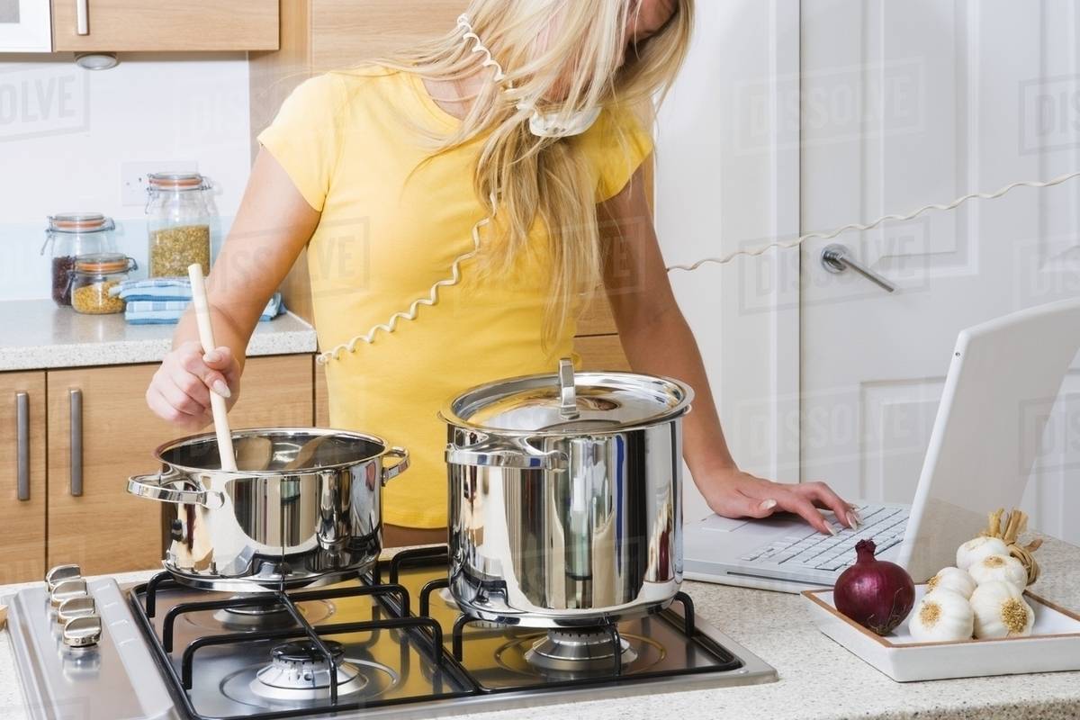 Woman cooking whilst on telephone and using laptop - Royalty-free Stock ...
