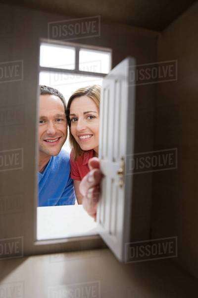 Young couple looking through door of model house - Royalty-free Stock ...