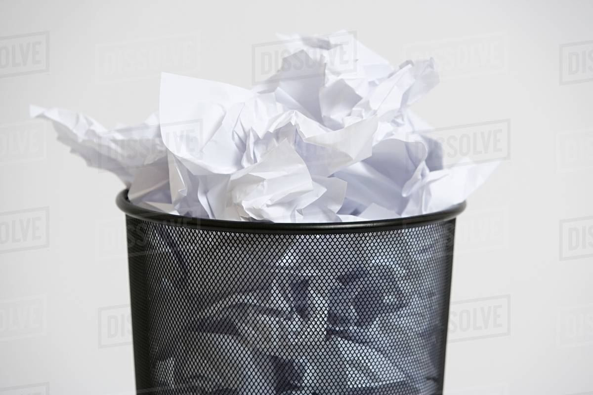 A wastepaper basket with crumpled up paper in it - Stock Photo - Dissolve