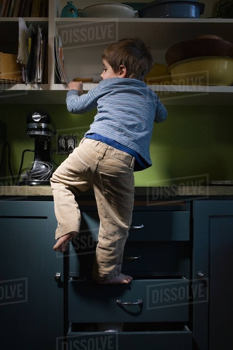 Boy climbing in kitchen - Royalty-free Stock Photo | Dissolve