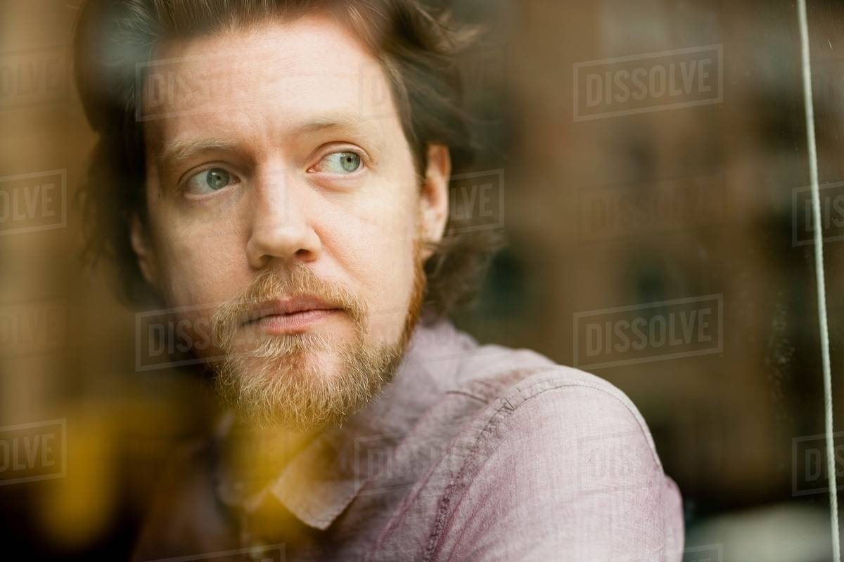 Man looking out of window - Stock Photo - Dissolve