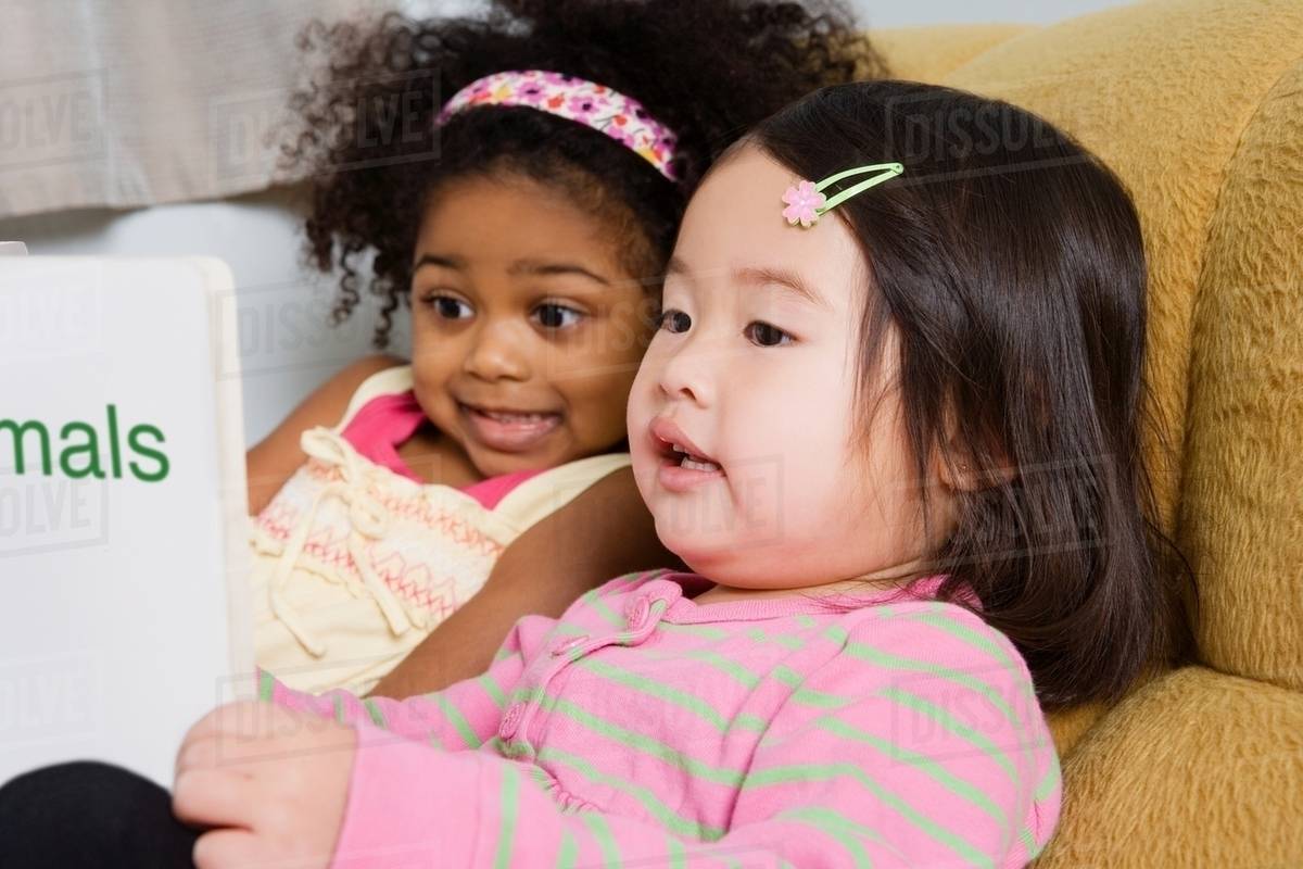 Two girls reading a book - Stock Photo - Dissolve