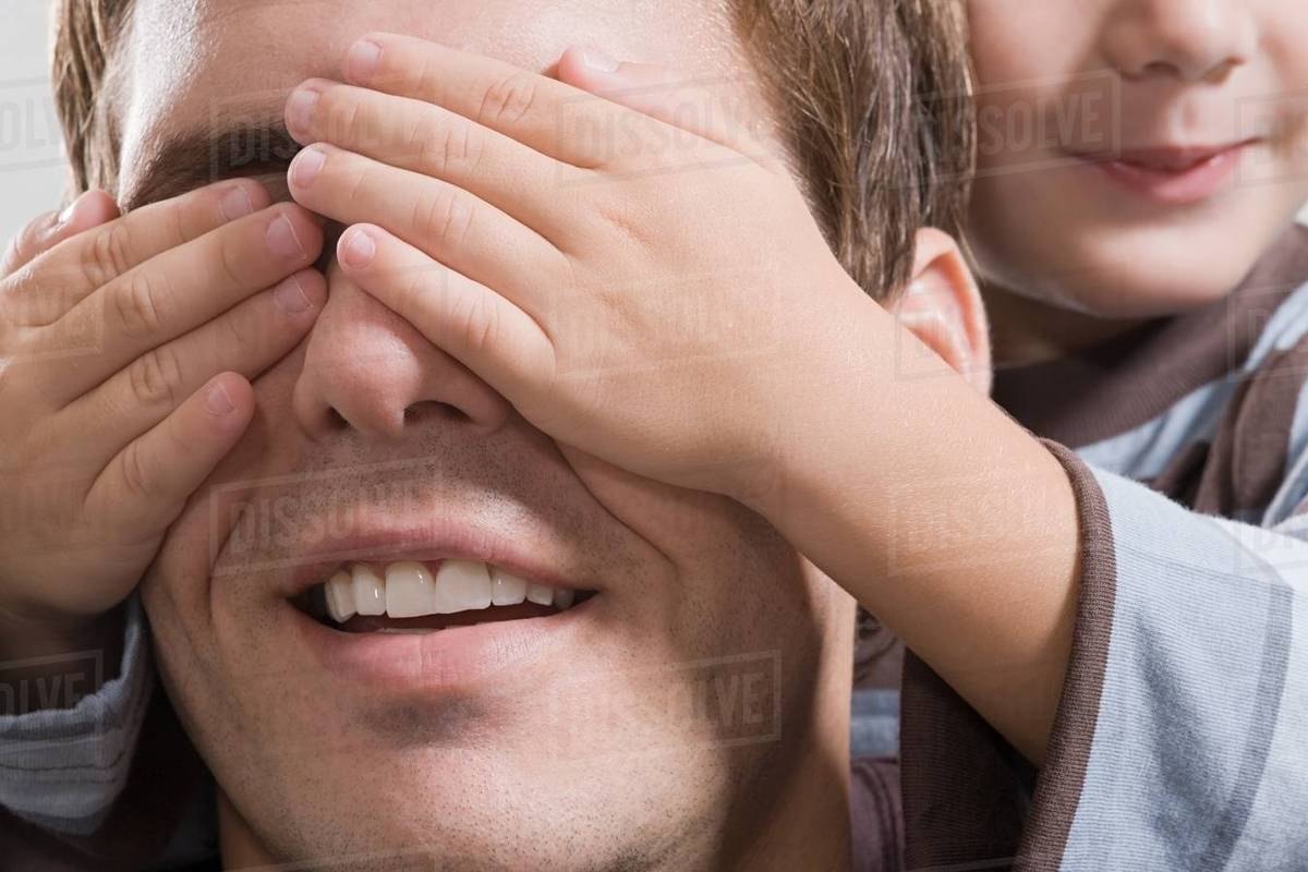 A son covering his fathers eye - Stock Photo - Dissolve