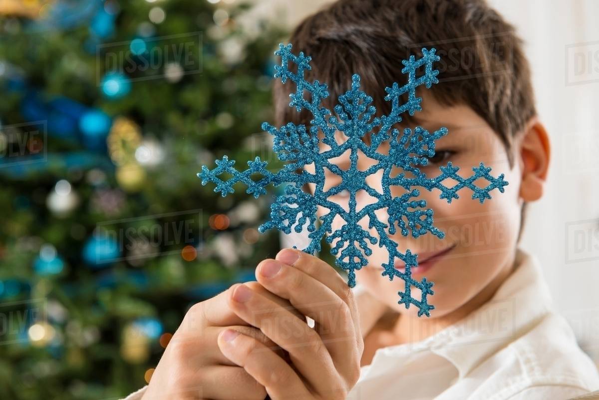 Boy holding blue snowflake decoration - Royalty-free Stock Photo | Dissolve
