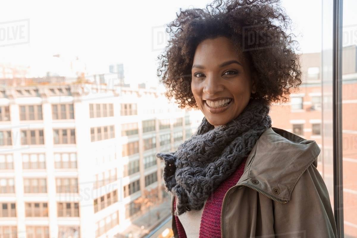 Smiling woman standing at window - Royalty-free Stock Photo | Dissolve