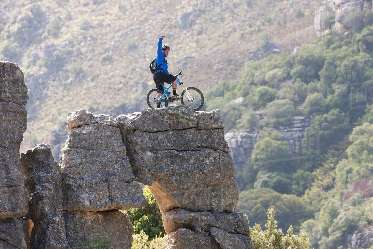Young man on mountain bike standing on rock formation - Stock Photo ...