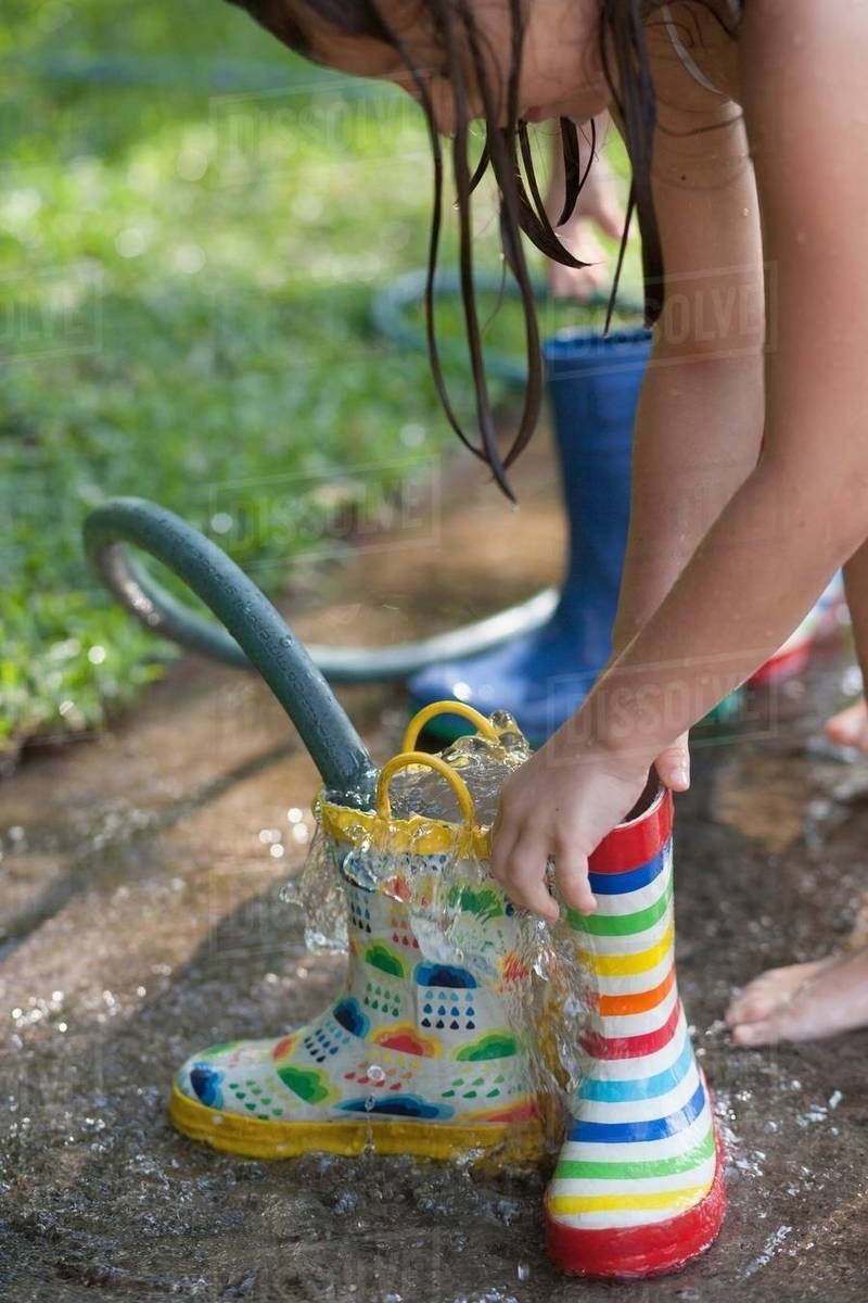Girl filling wellies with water from hose - Royalty-free Stock Photo ...