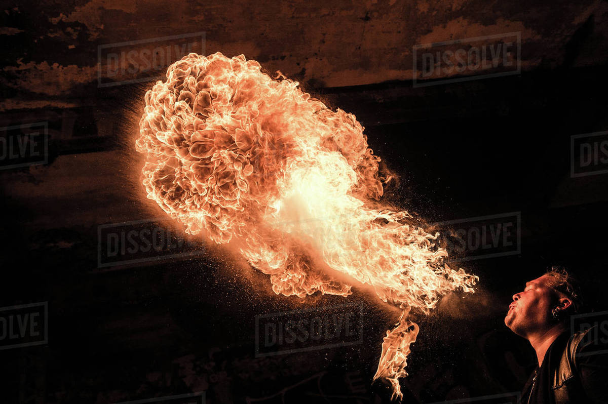 Low angle view of man fire breathing - Stock Photo - Dissolve
