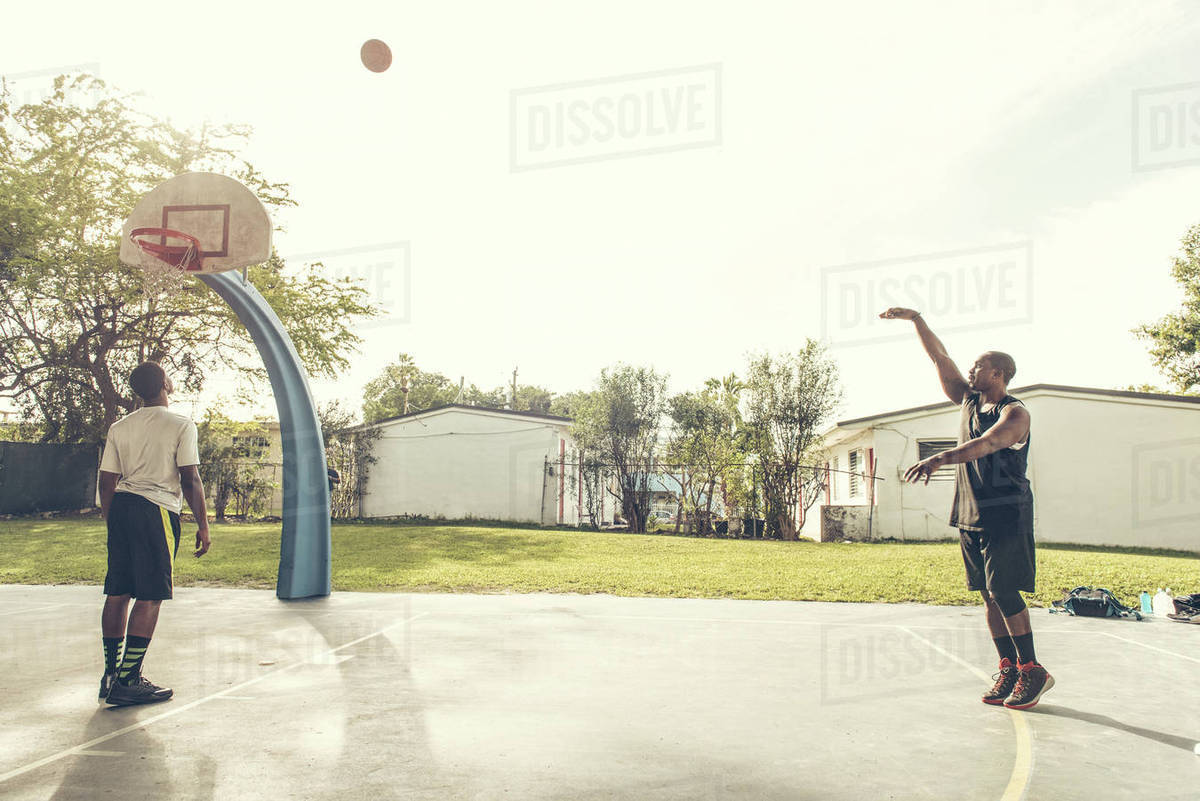 Men on basketball court scoring basketball hoops - Stock Photo - Dissolve