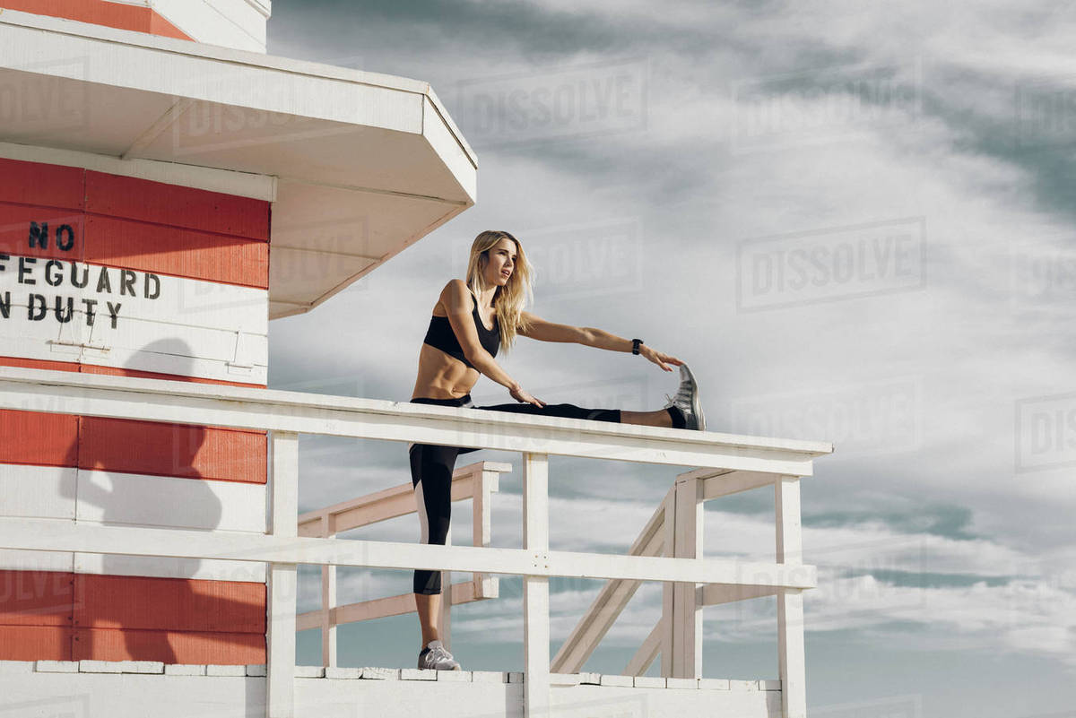 Young woman on lifeguard platform, exercising - Stock Photo - Dissolve