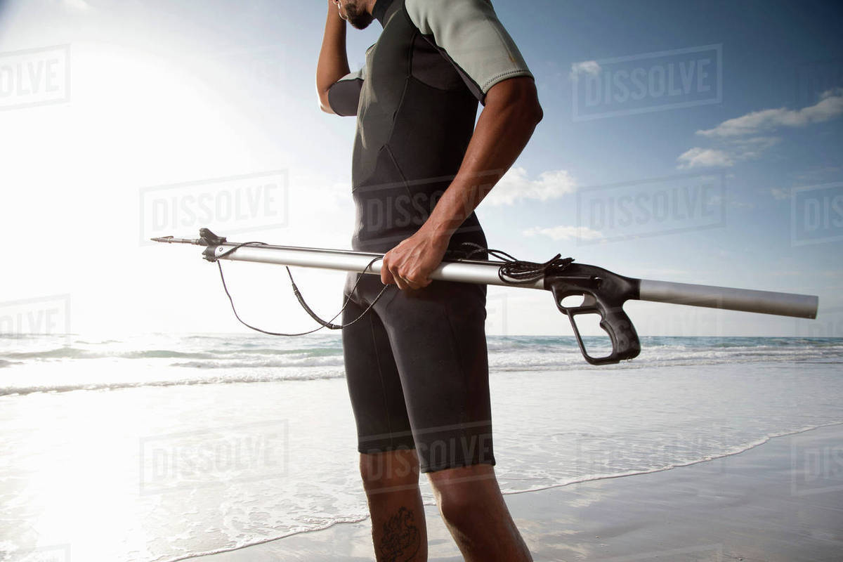 Diver with speargun on beach - Royalty-free Stock Photo | Dissolve