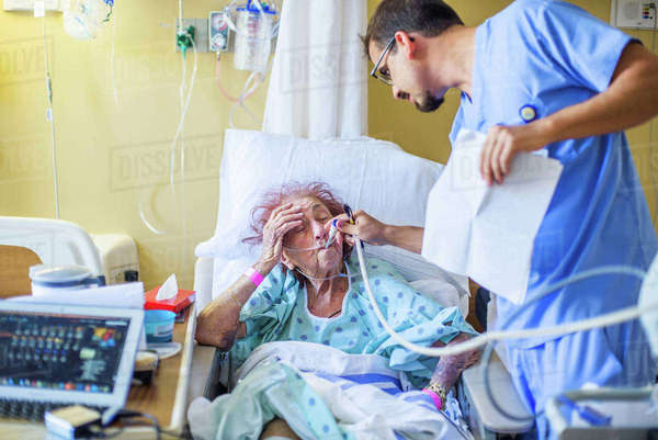 Hospital staff checking on patient on hospital bed - Stock Photo - Dissolve