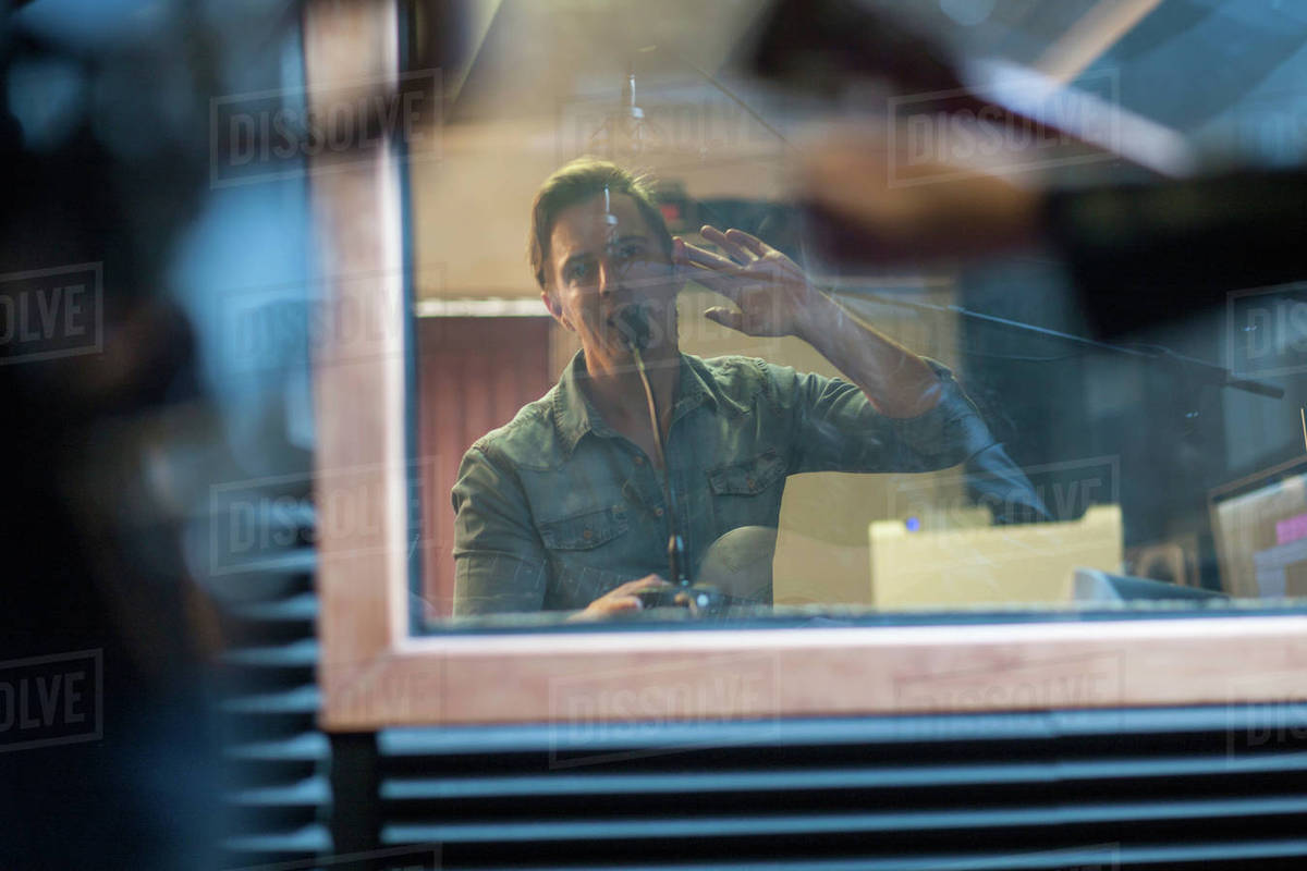 Musicians in recording studio, music producer communicating to them ...