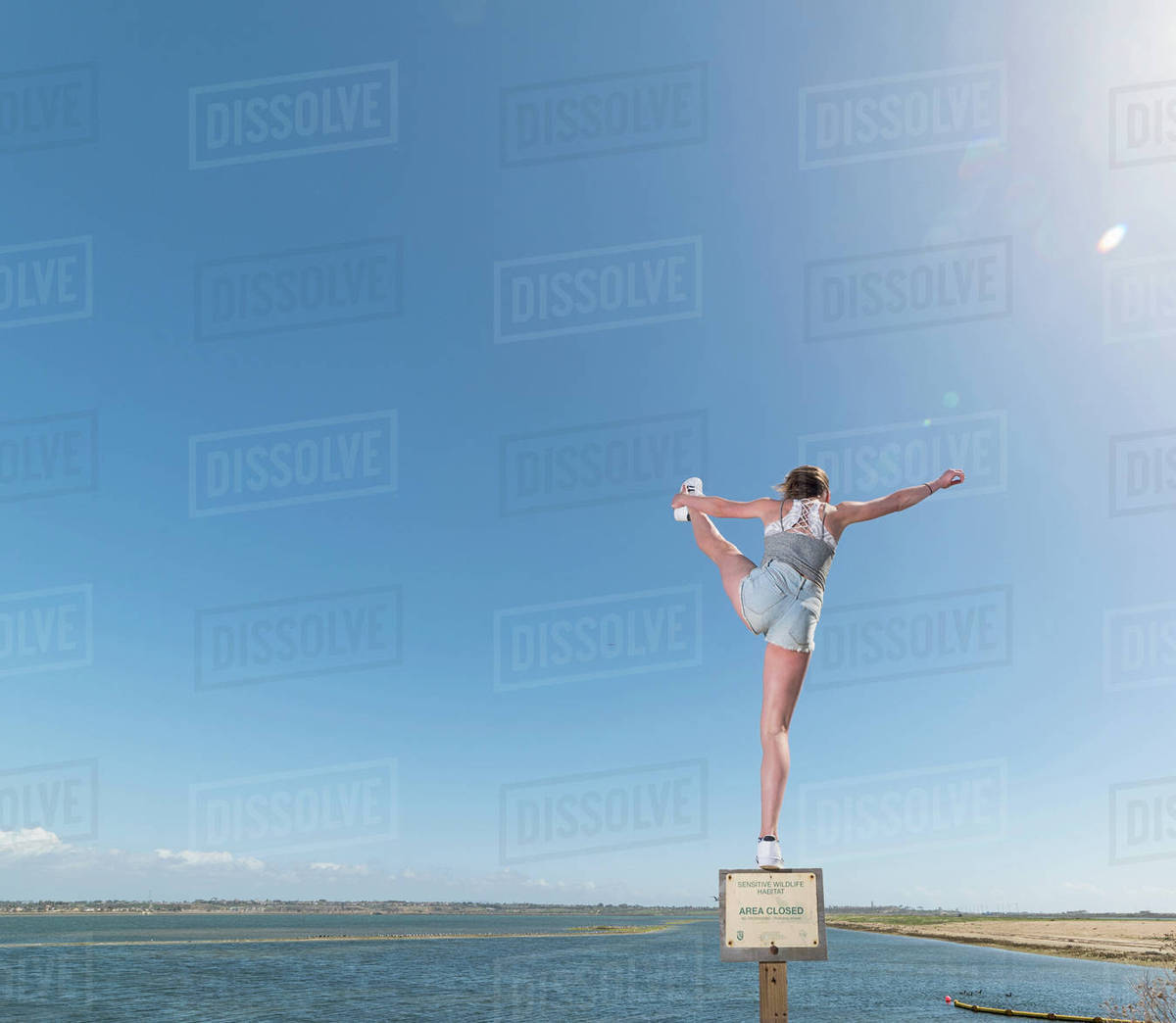 Girl balancing on beach signage - Royalty-free Stock Photo | Dissolve