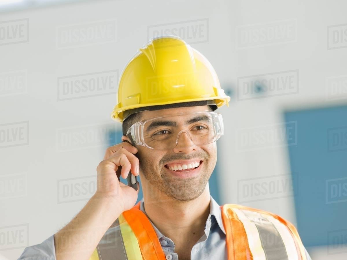 Mid adult construction worker using mobile phone, smiling - Royalty ...