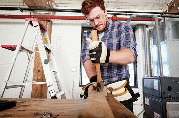 Carpenter in workshop removing nails form timber using hammer - Royalty ...