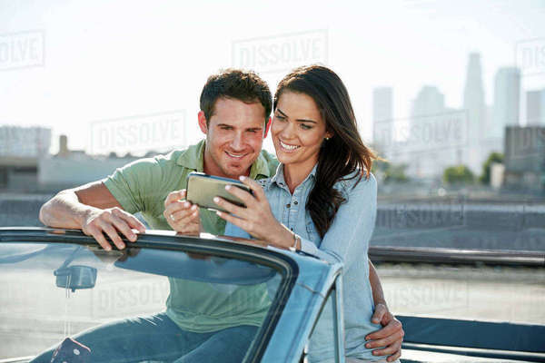 Couple in convertible car looking at smartphone, Los Angeles ...